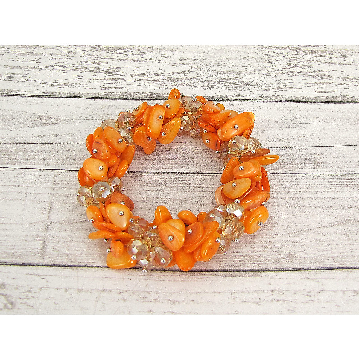 Calisa Designs Woman's orange shell and glass beaded stretch bracelet with silver beads, Designed with clusters of orange shell and orange facet cut glass beads.