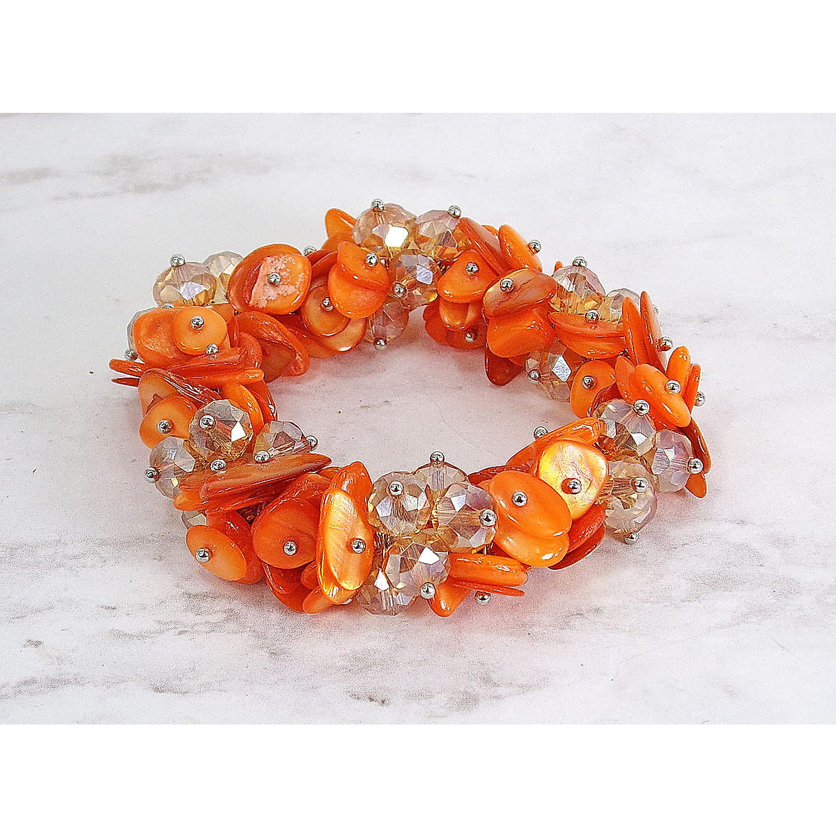 Calisa Designs Woman's orange shell and glass beaded stretch bracelet with silver beads, Designed with clusters of orange shell and orange facet cut glass beads.