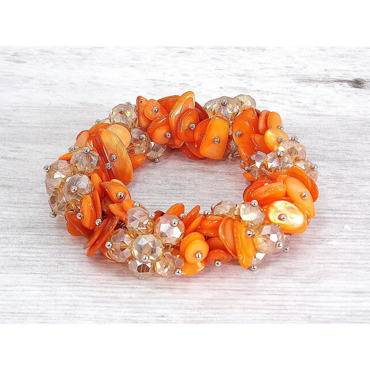 Calisa Designs Woman's orange shell and glass beaded stretch bracelet with silver beads, Designed with clusters of orange shell and orange facet cut glass beads.